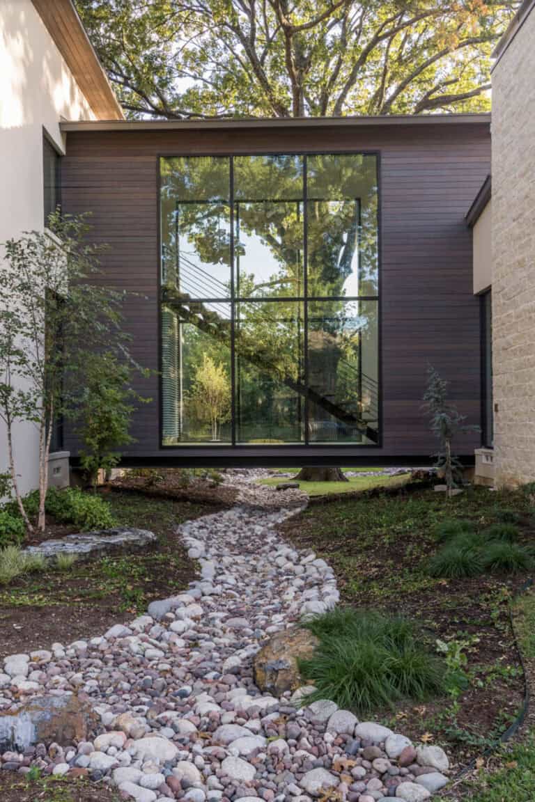 This striking Dallas home features a glass bridge over a serene landscape